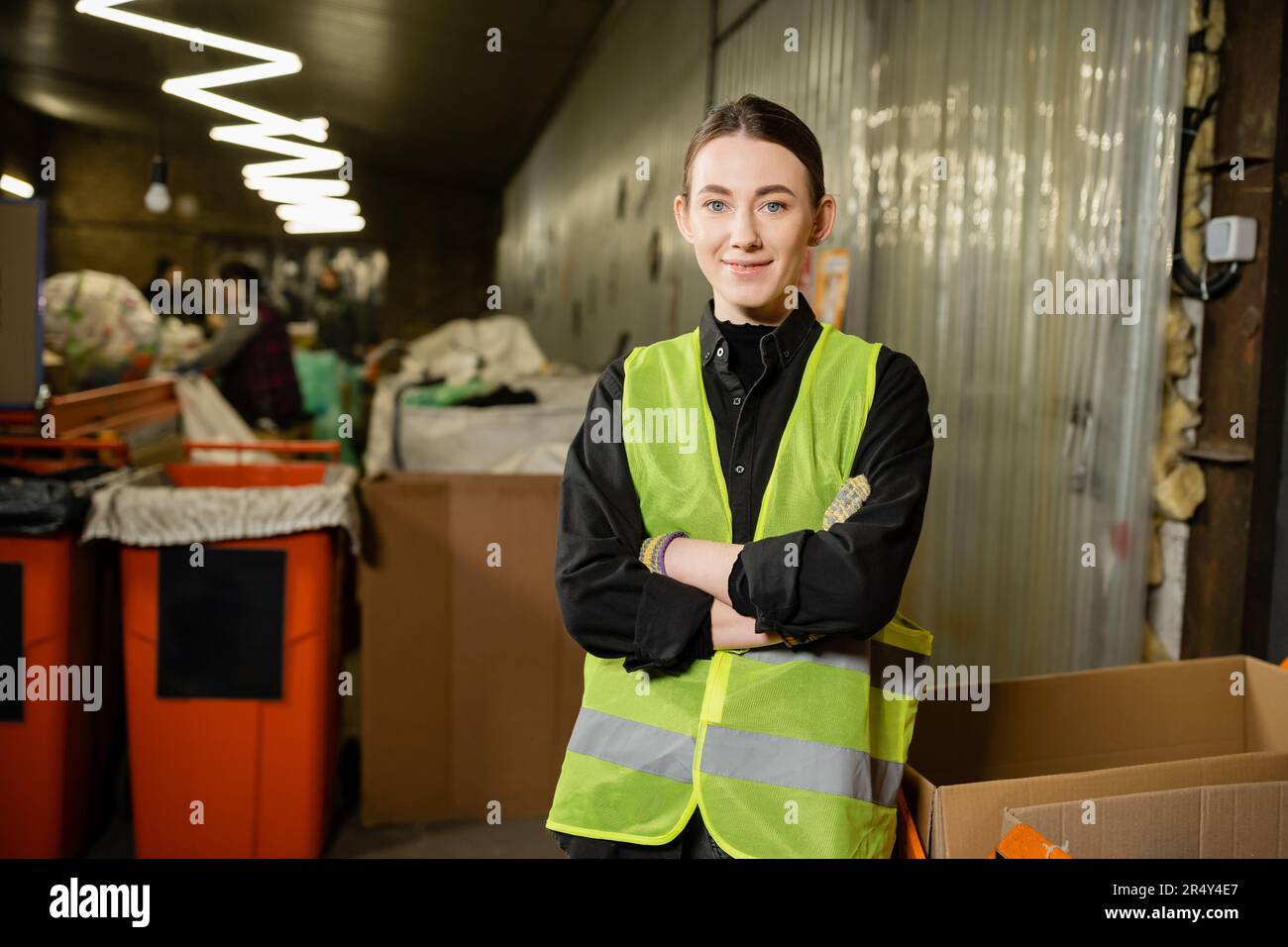 Young and smiling worker of waste disposal station in high visibility ...
