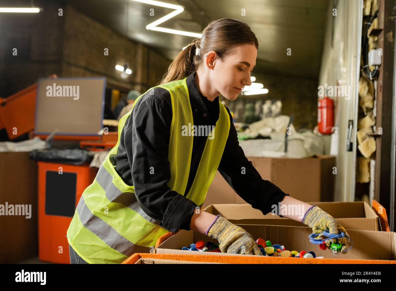 Young female worker of garbage sorting center wearing protective ...