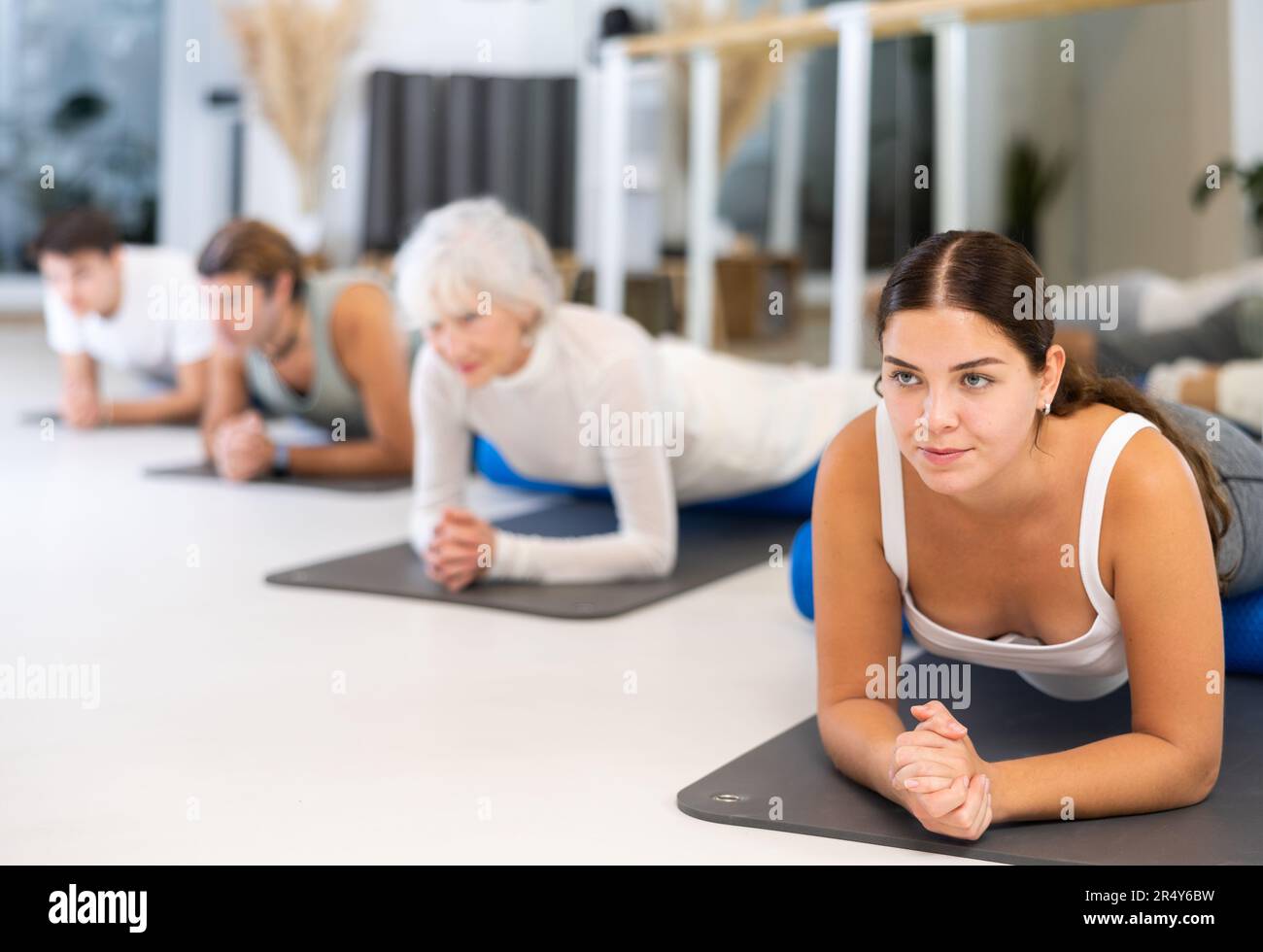 Women and men practicing yoga positions during group training in ...