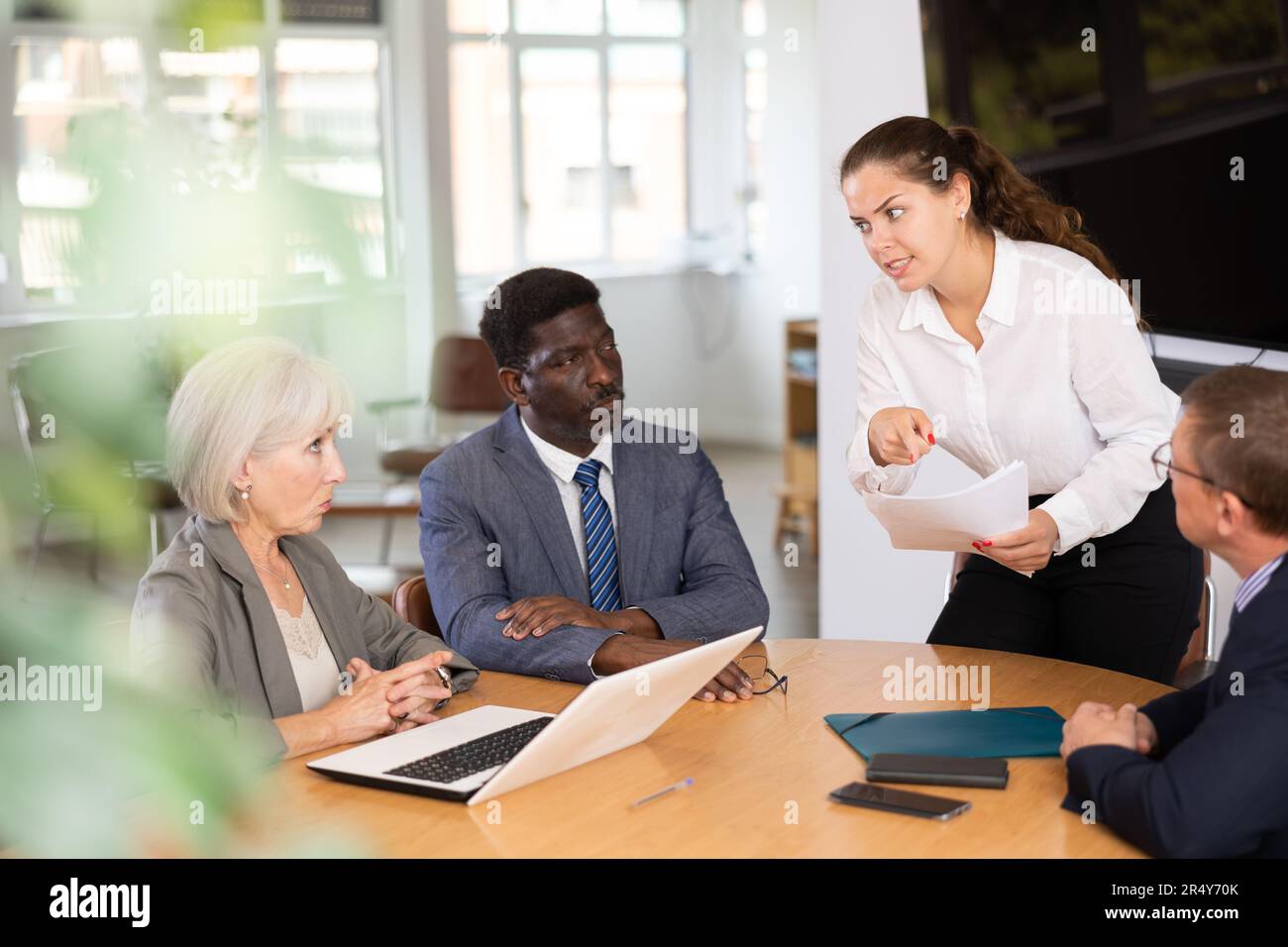 Angry young woman shouting at her business partners sitting around ...