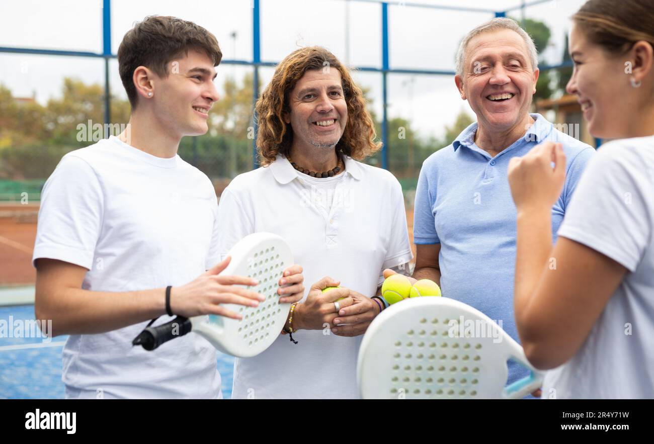 Happy people with rackets for padel talking on court Stock Photo - Alamy