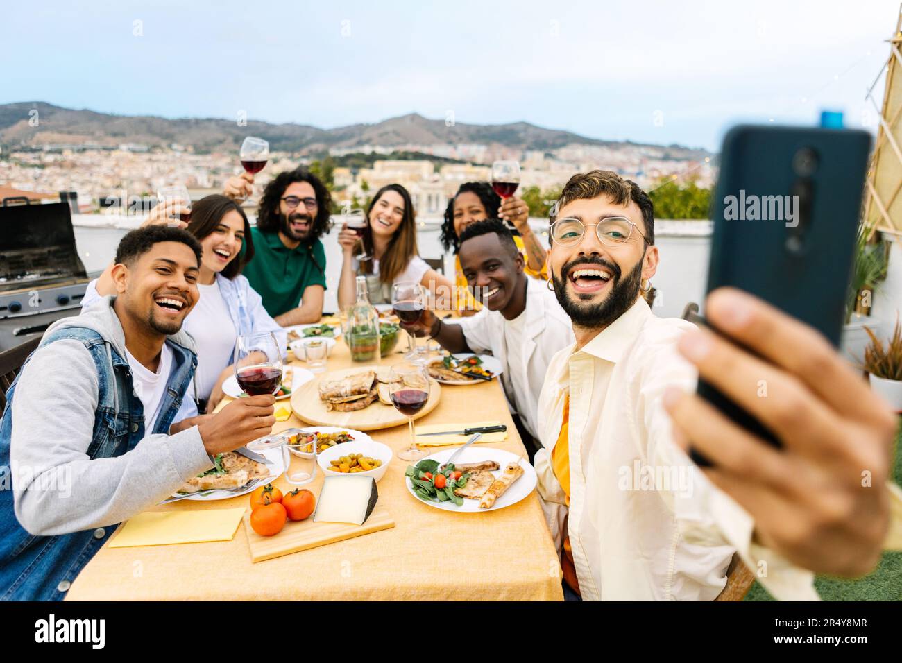 Young group of friends gathered sitting around a table enjoying a ...