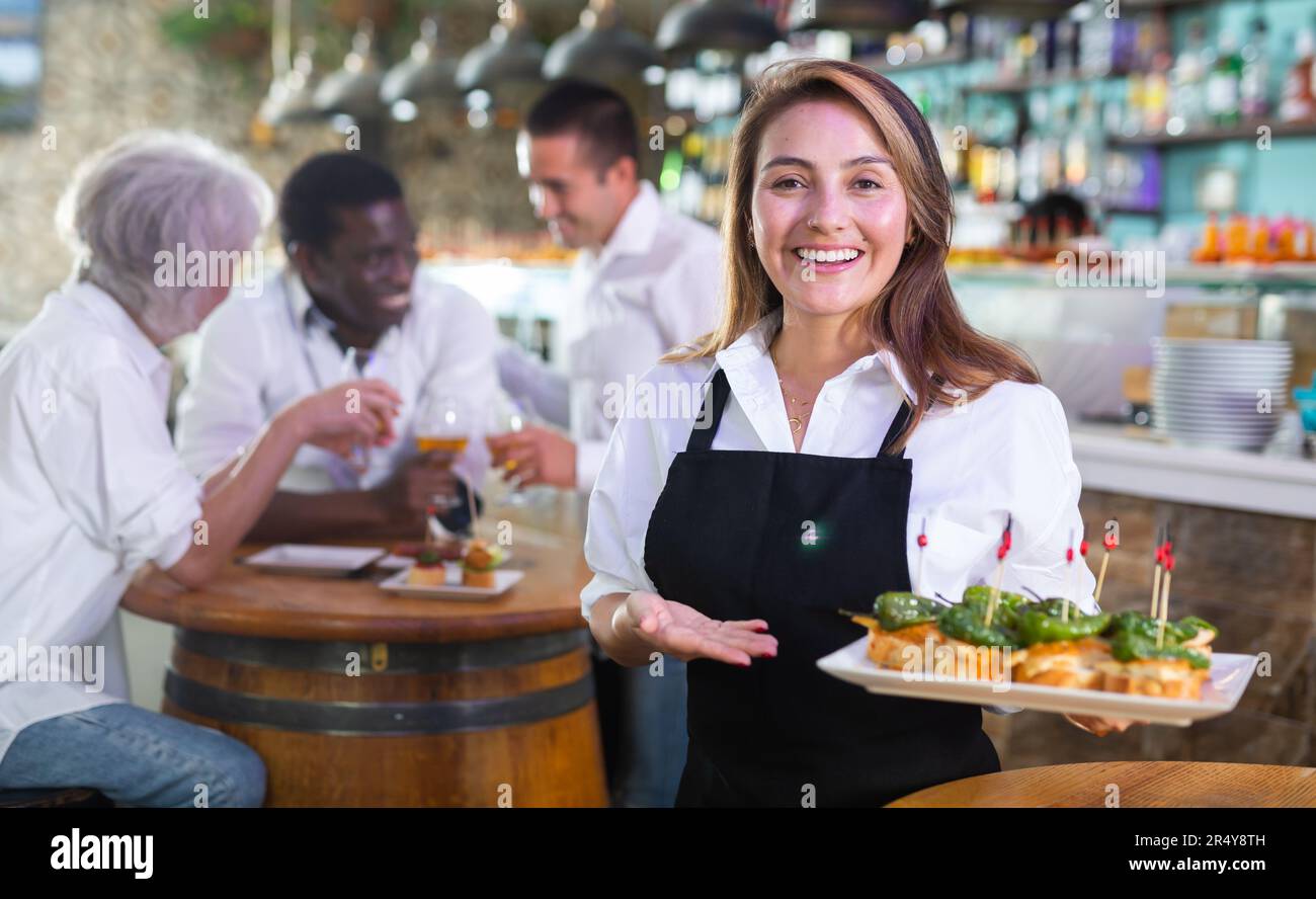 Positive waiter holding tray with pinchos at restaurant Stock Photo - Alamy