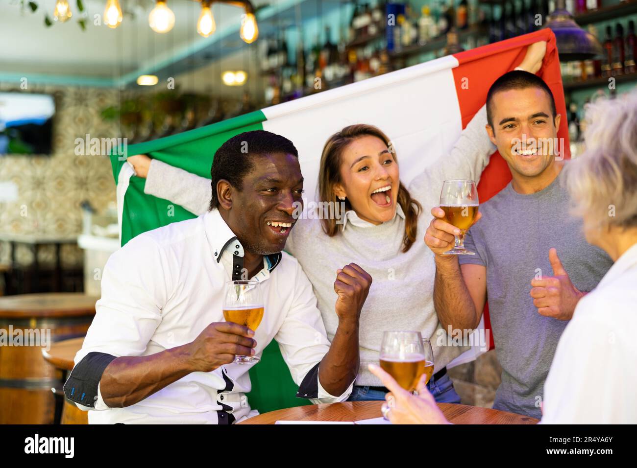 Happy multiracial friends holding the flag of Italy, supporting ...