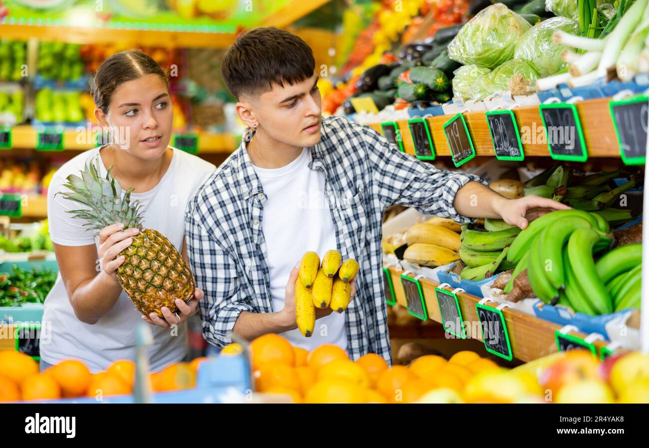 Married couple picks and buys bananas and pineapple in vegetable ...