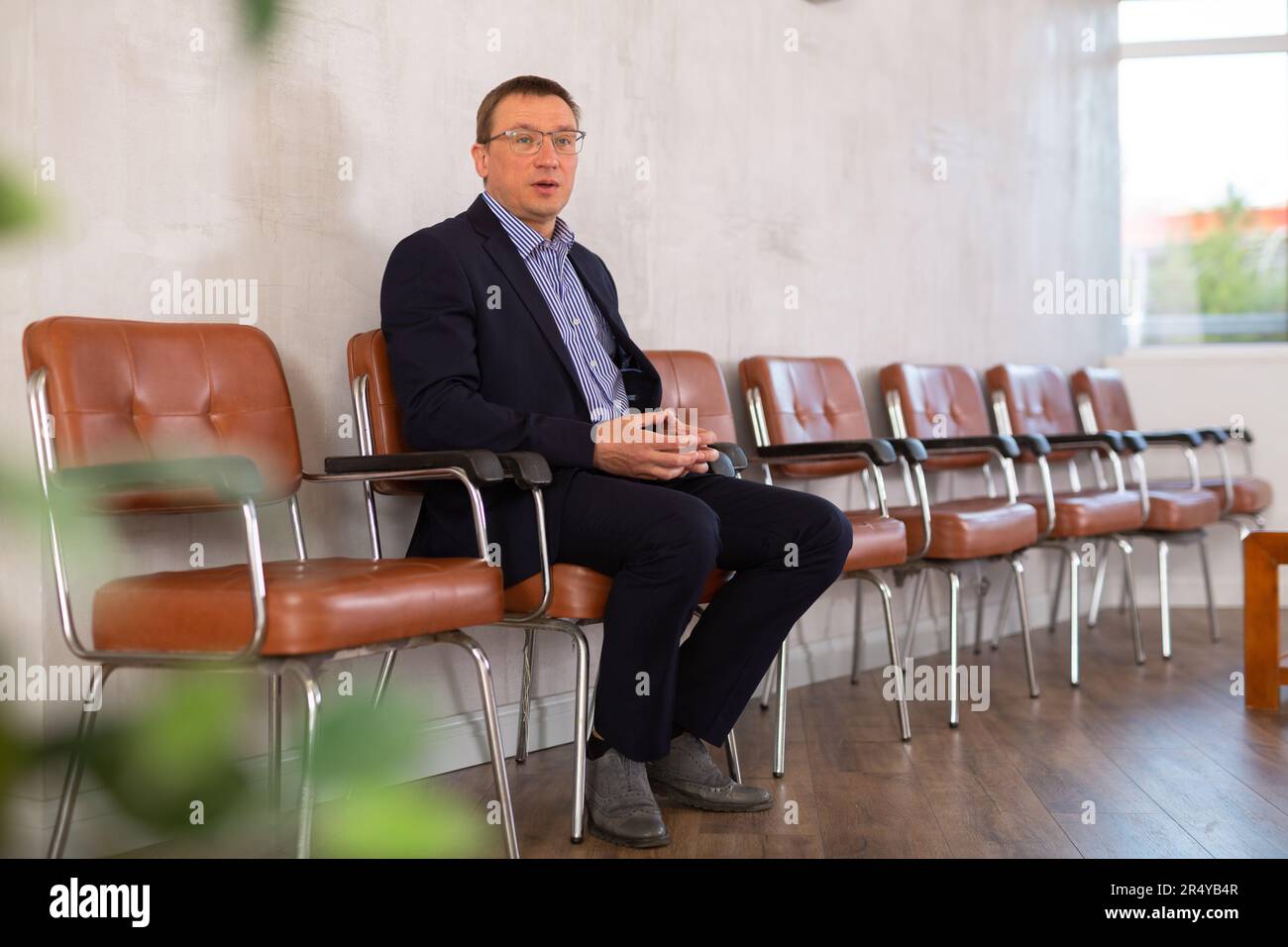 Serious-minded male candidate siting on chair and waiting for job ...