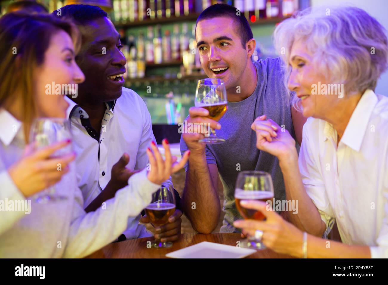 Company of multiracial friends drinking beer and talking with each ...