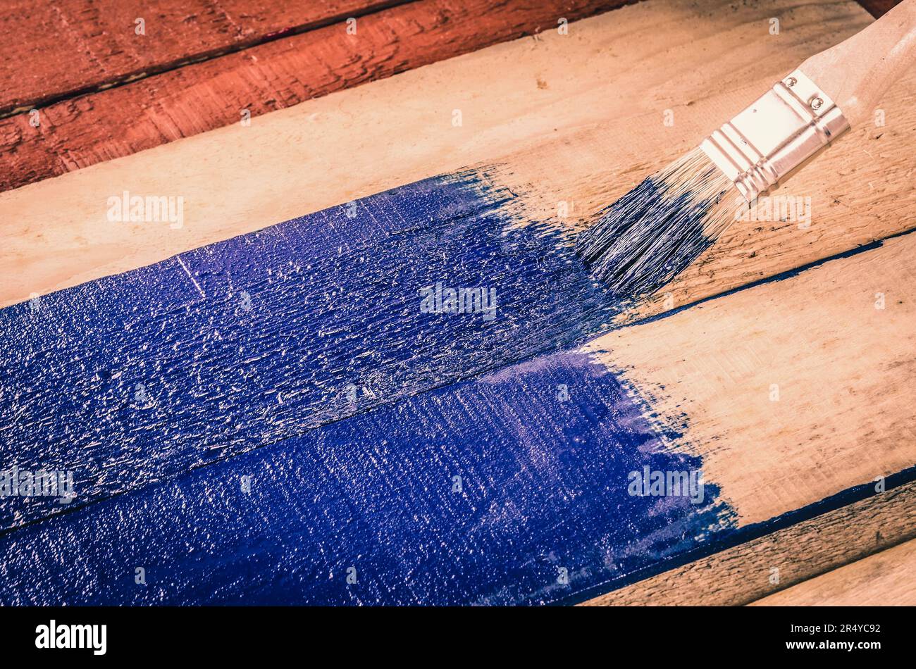 Brush,paint and wooden boards. Painting the boards with blue paint ...