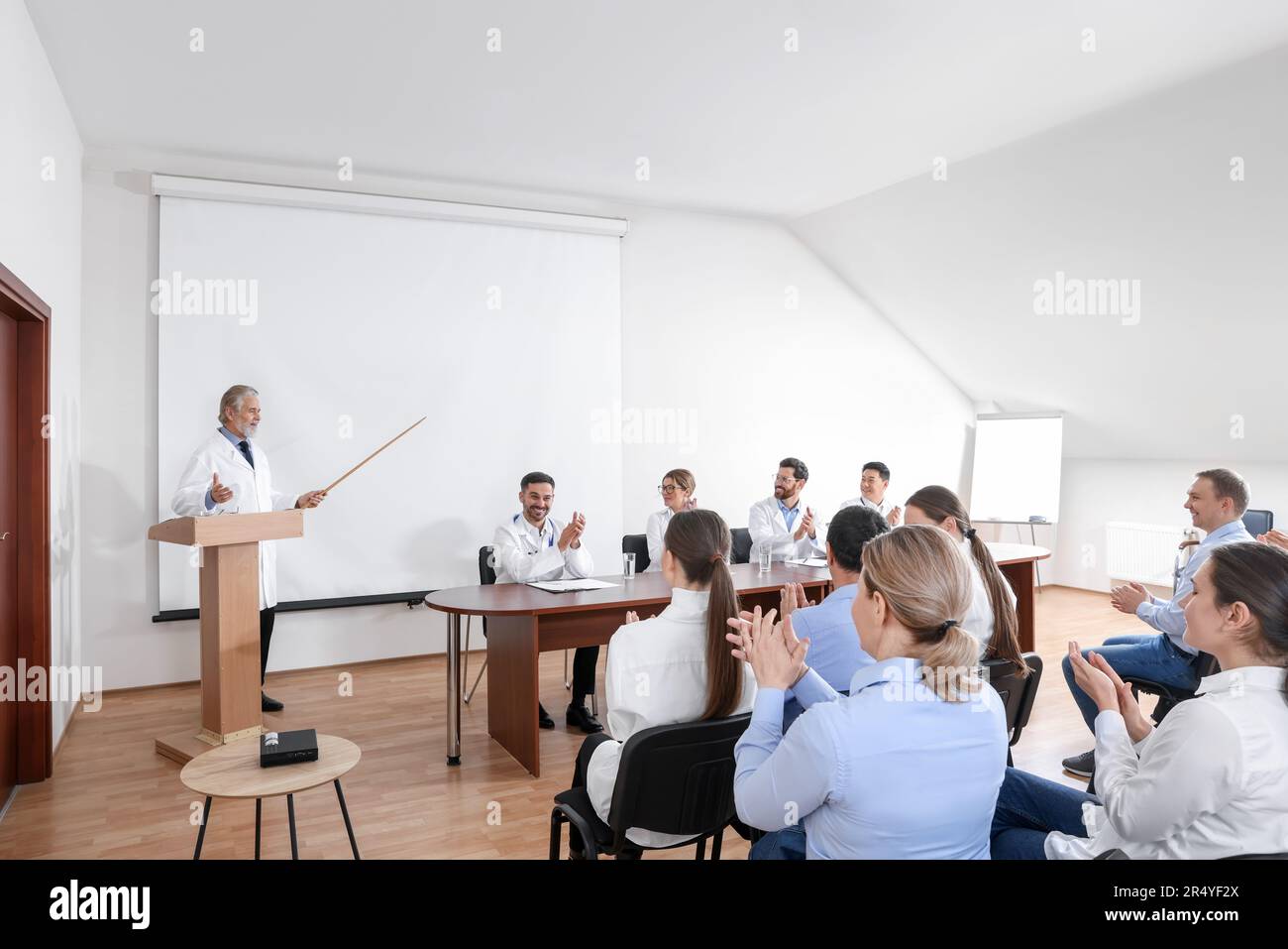 Senior doctor giving lecture in conference room with projection screen ...