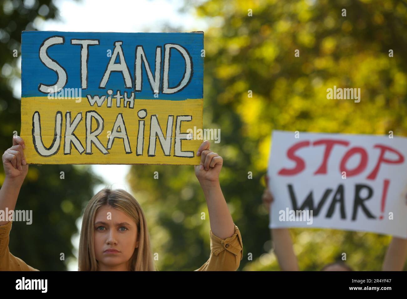 Sad woman holding poster in colors of national flag and words Stand ...