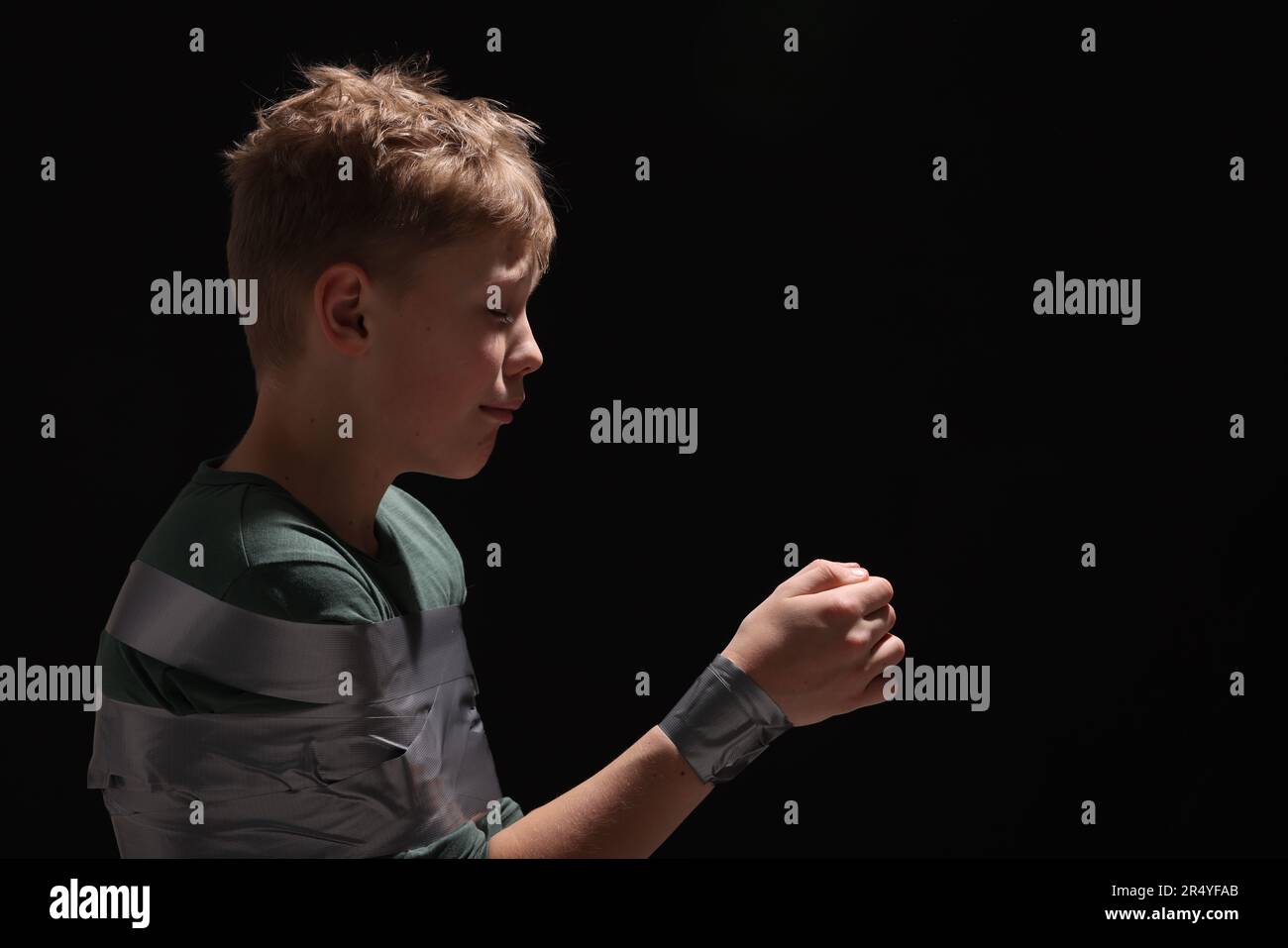 Little boy tied up and taken hostage on dark background. Space for text ...