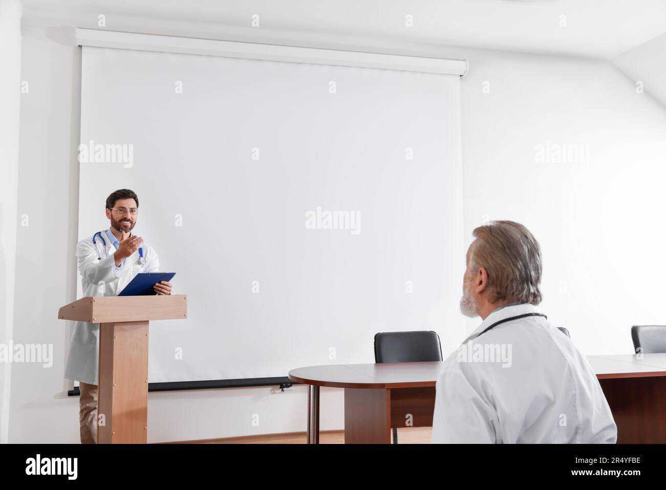 Doctor giving lecture in conference room with projection screen Stock ...