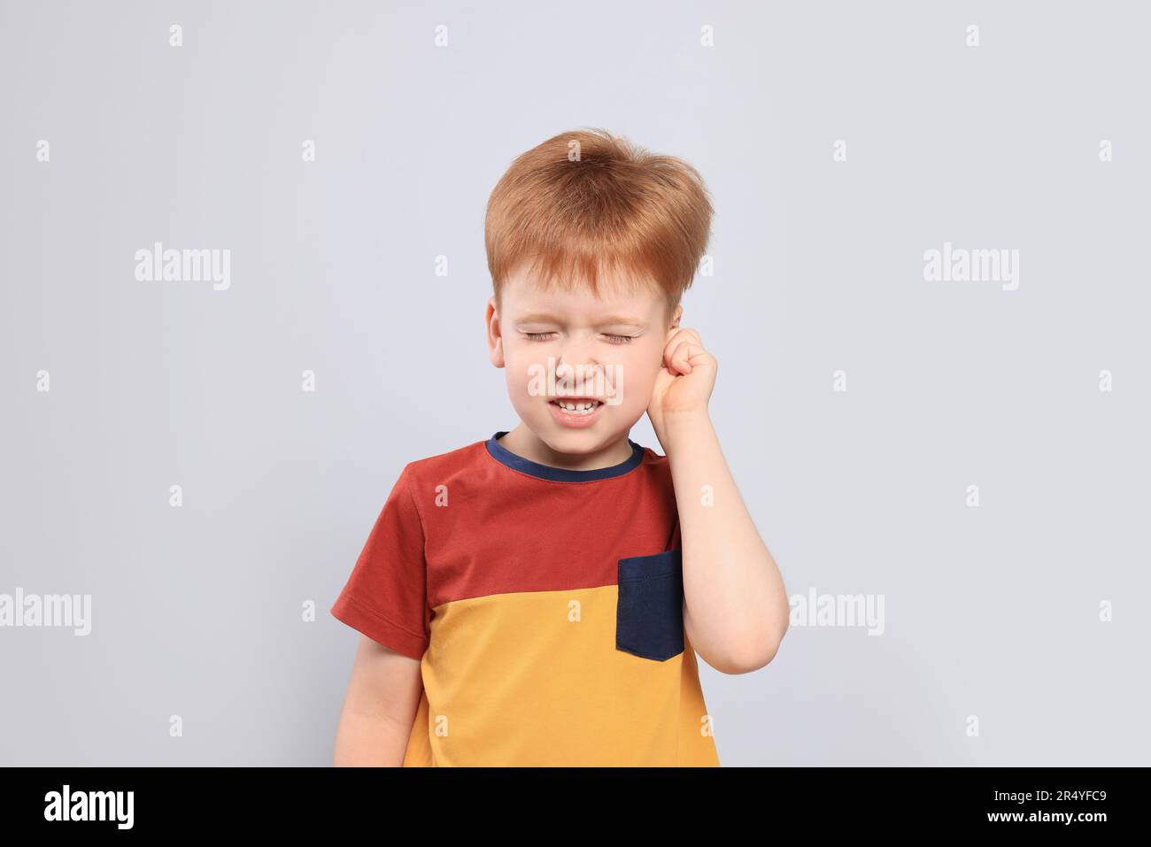 Little boy suffering from ear pain on light grey background Stock Photo ...
