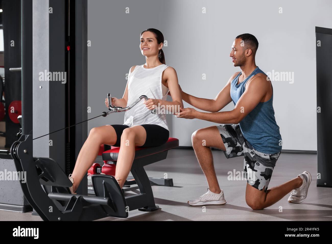 Trainer explaining woman how to do exercise properly in modern gym ...
