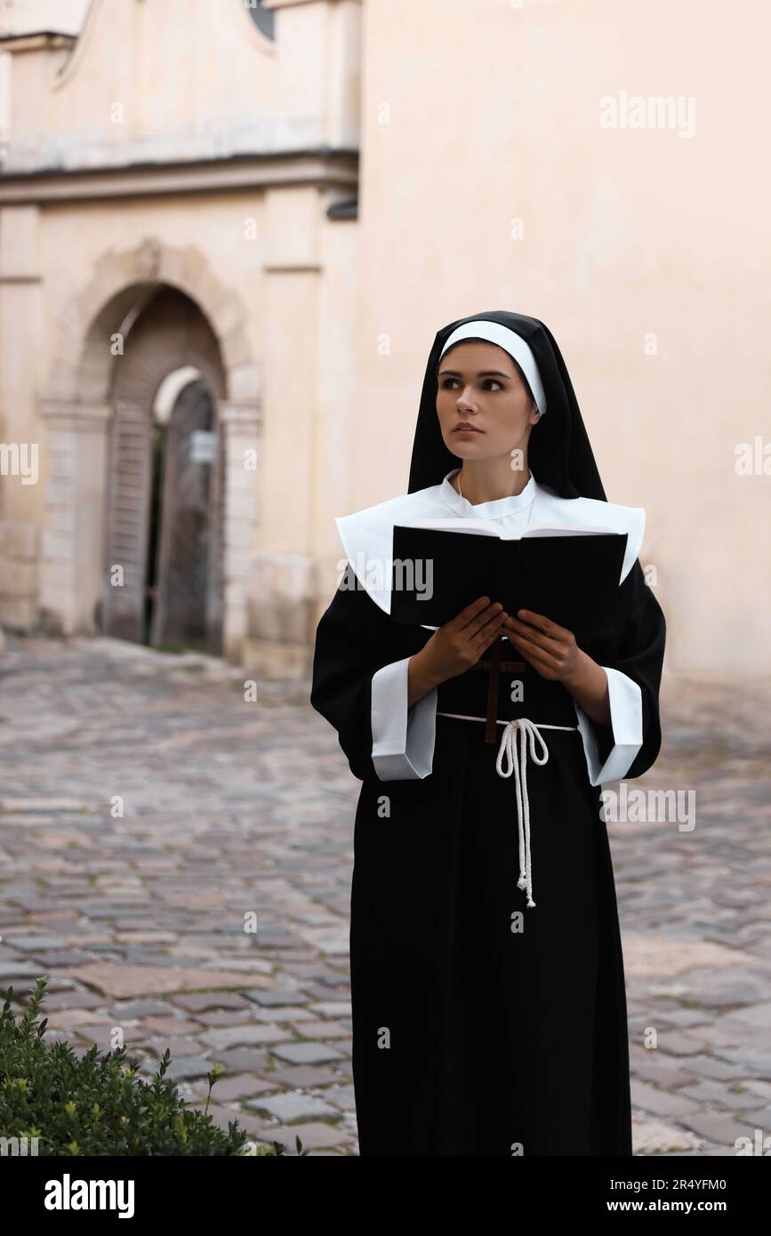 Young nun reading Bible on city street Stock Photo - Alamy