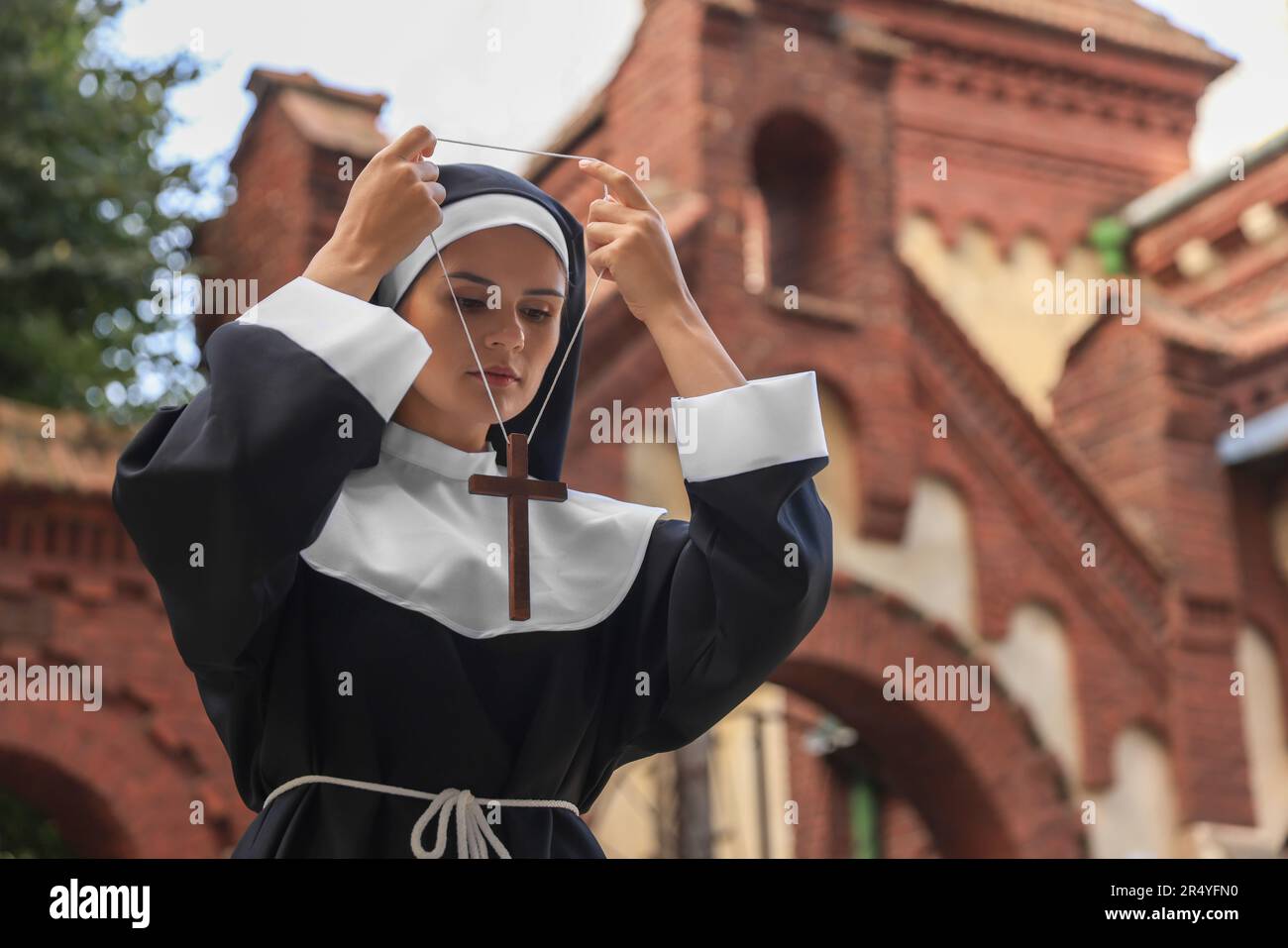 Young nun wearing Christian cross near building outdoors Stock Photo ...