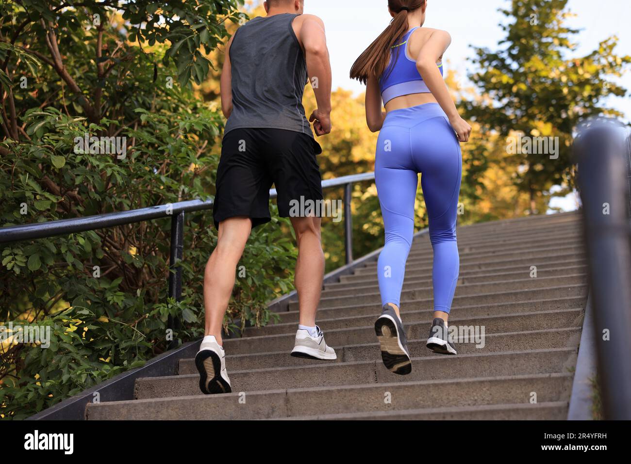 Sporty couple running up stairs outdoors on sunny day, back view Stock ...