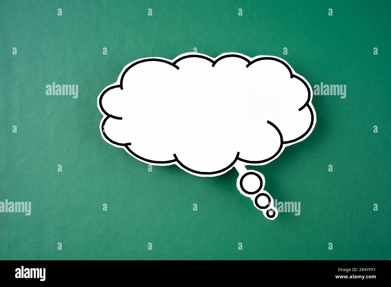 White speech bubble shaped post it note on green background with copy ...