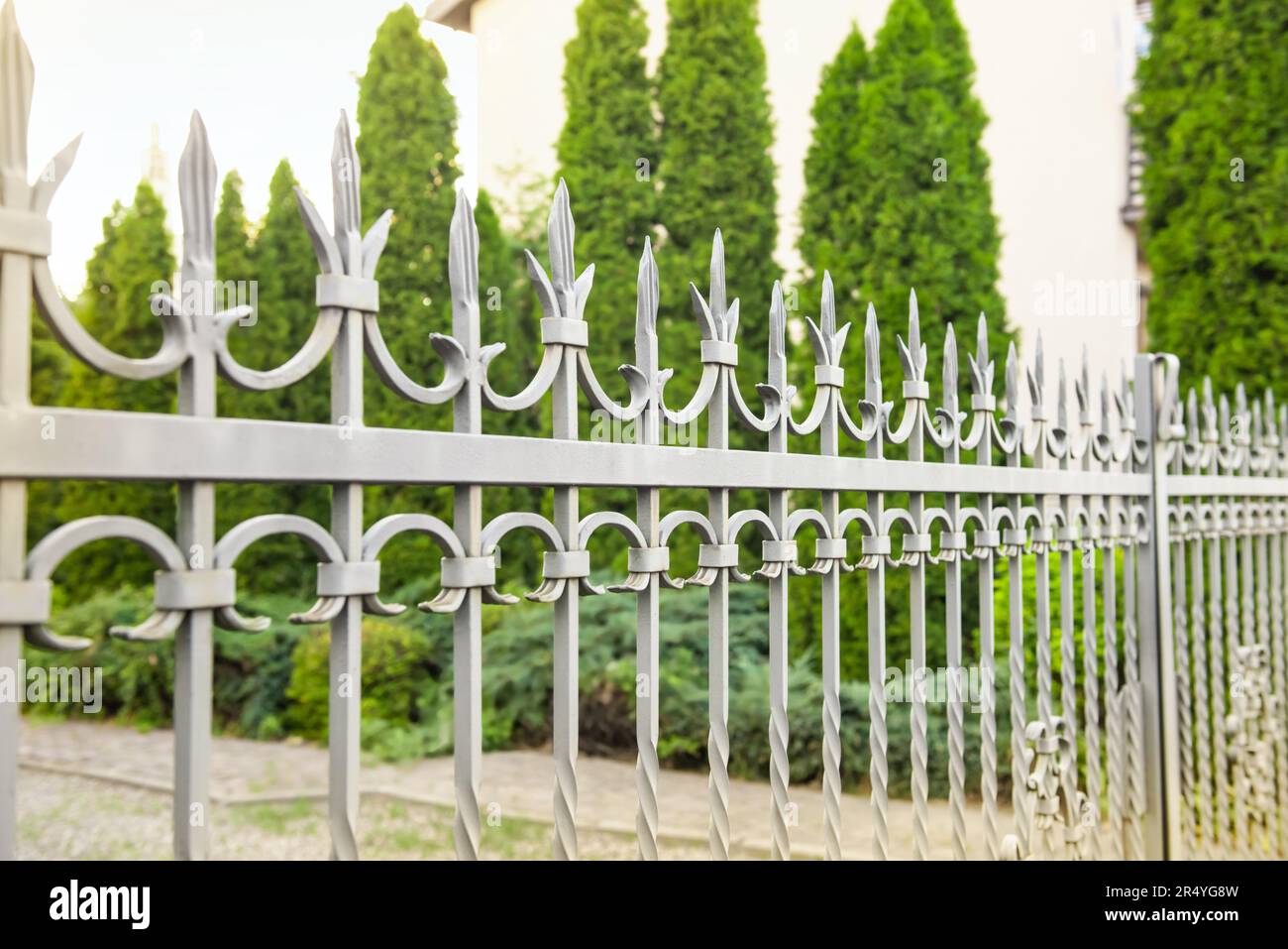 Trees behind beautiful iron fence near pathway outdoors Stock Photo - Alamy