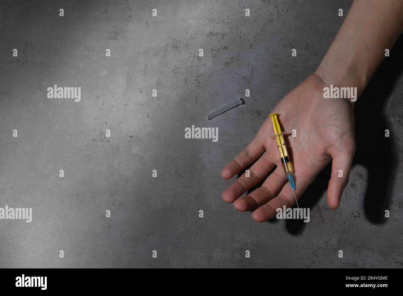 Drug addiction. Man with syringe on grey table, top view and space for ...