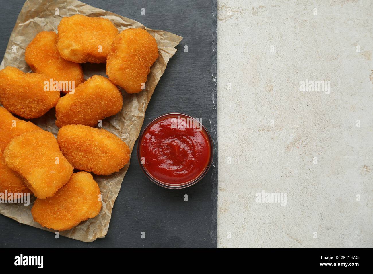Tasty chicken nuggets with ketchup on light grey textured table, top ...