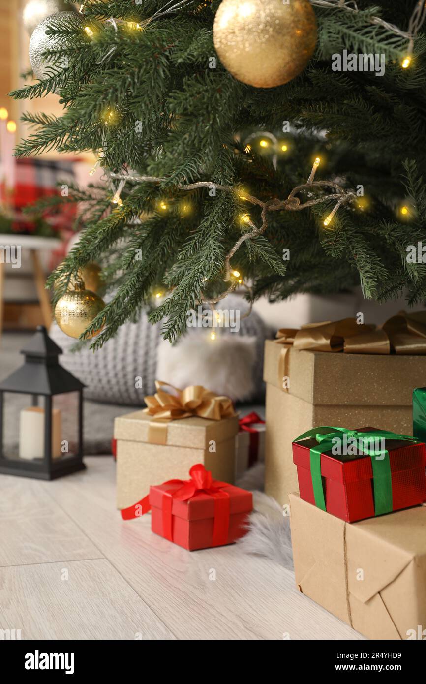 Gift boxes under Christmas tree and lantern with candle indoors Stock ...