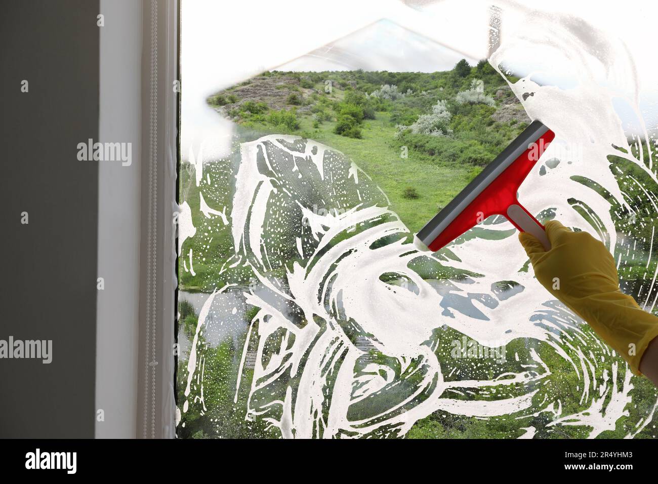 Worker cleaning window with squeegee, closeup. View through clear glass ...