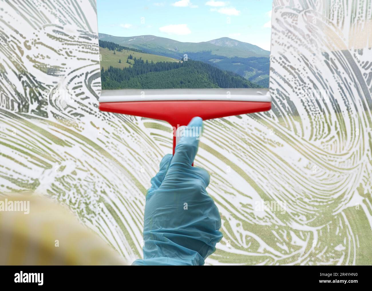 Worker cleaning window with squeegee, closeup. View through clear glass ...