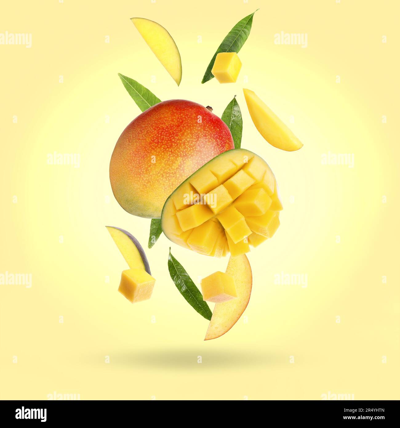 Delicious mango fruits and leaves falling on pale yellow background ...
