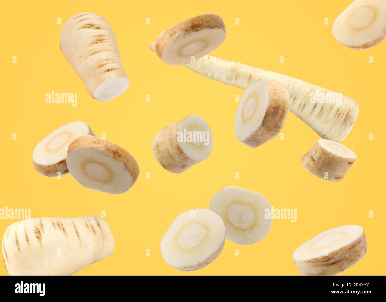 Pieces of parsnip root falling on pale orange background Stock Photo ...