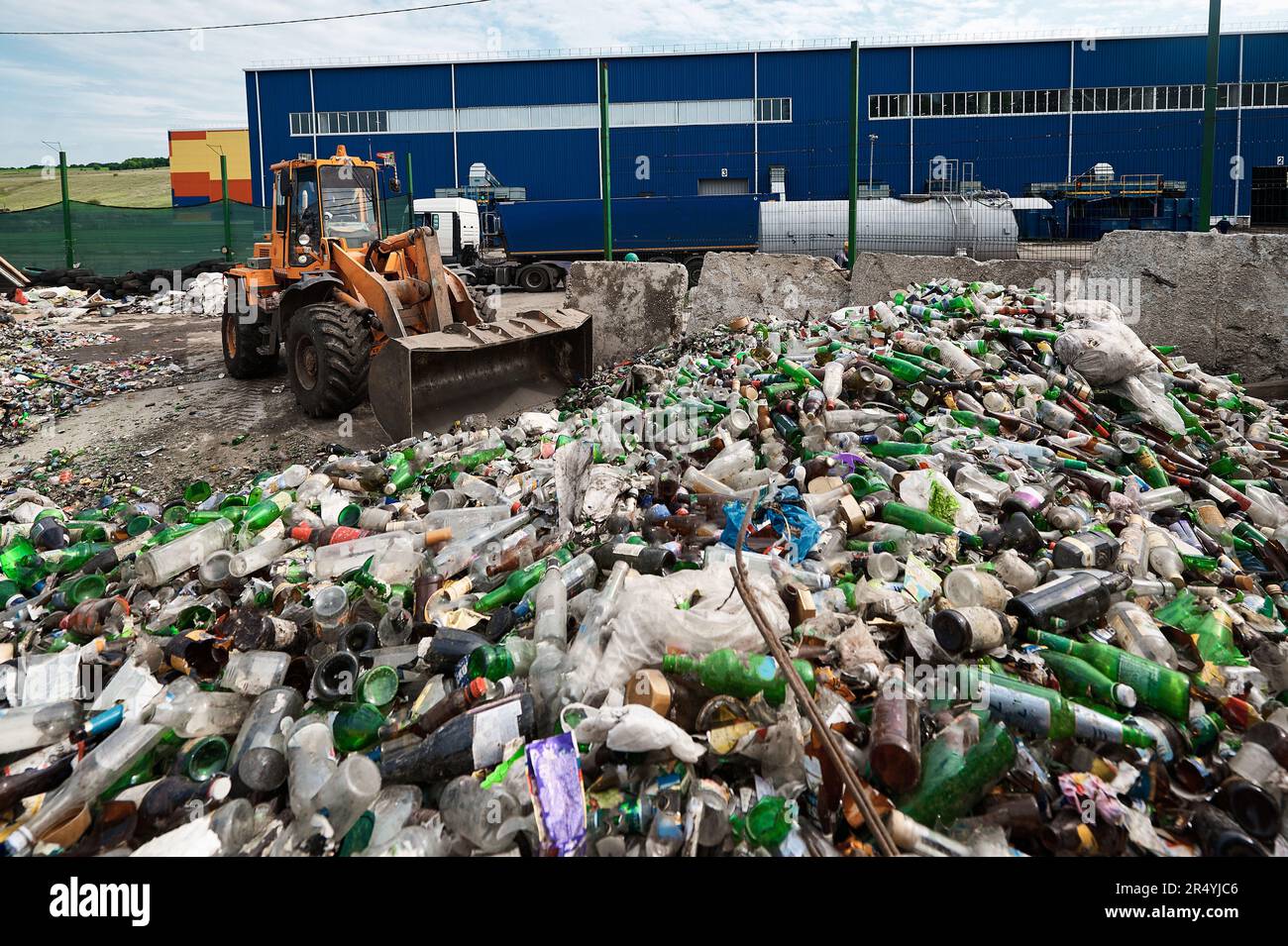 The bucket loader breaks glass bottles by dumping them out of the ...