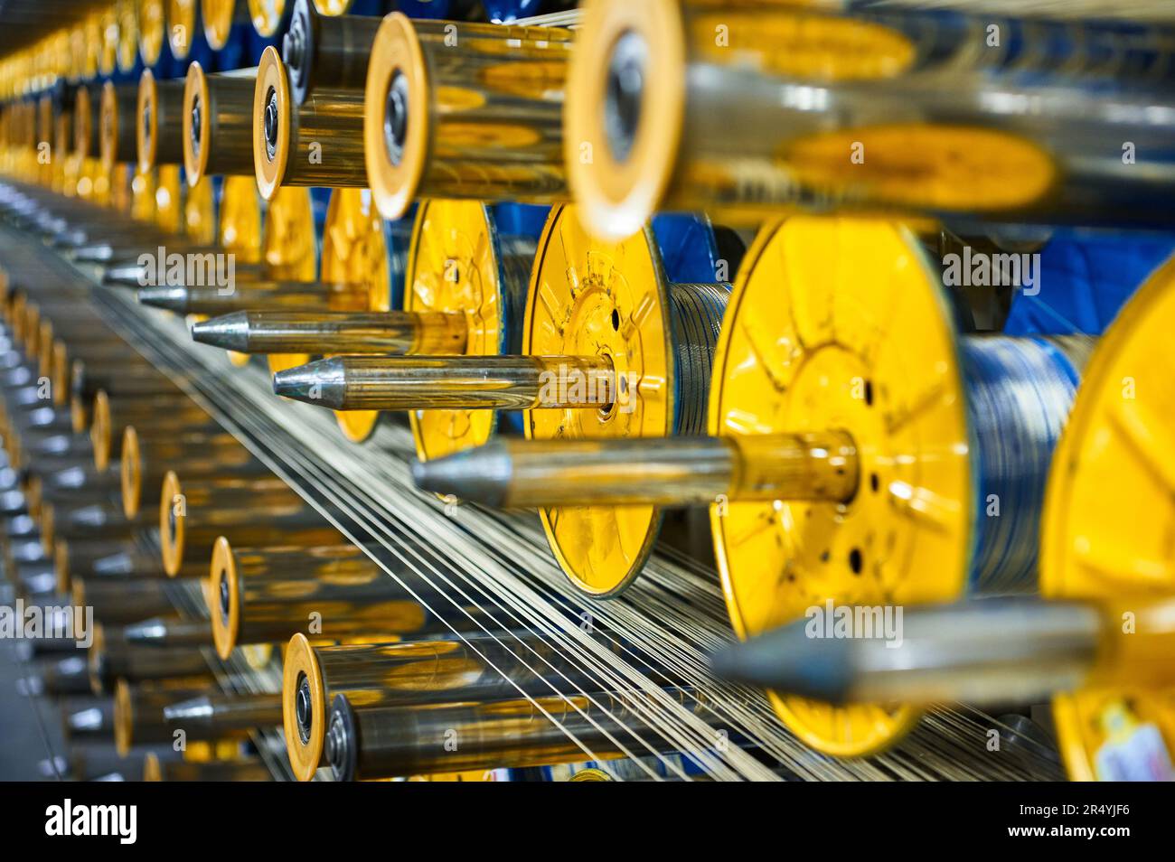 Yellow bobbins and metal spools in production workshop Stock Photo - Alamy
