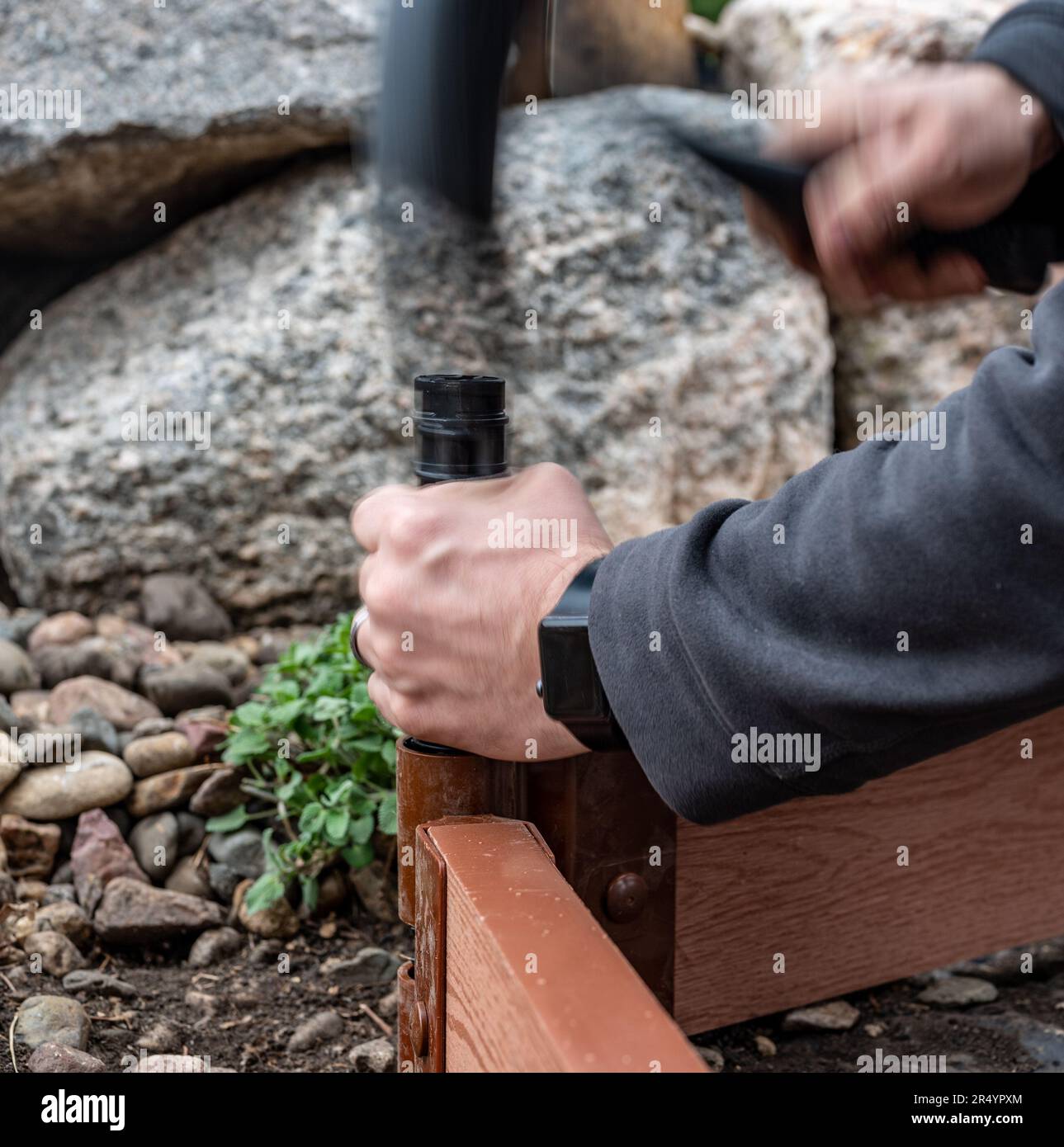 Actively driving a border stake with a rubber mallet to assemble a ...