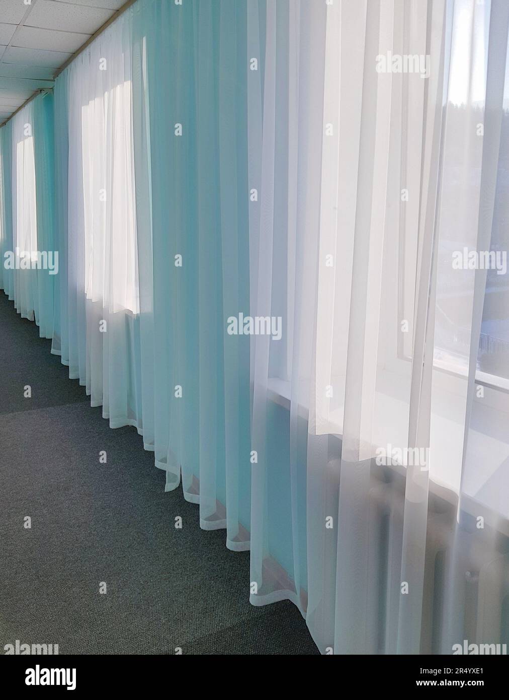 The prospect of a long hotel corridor with transparent curtains on ...