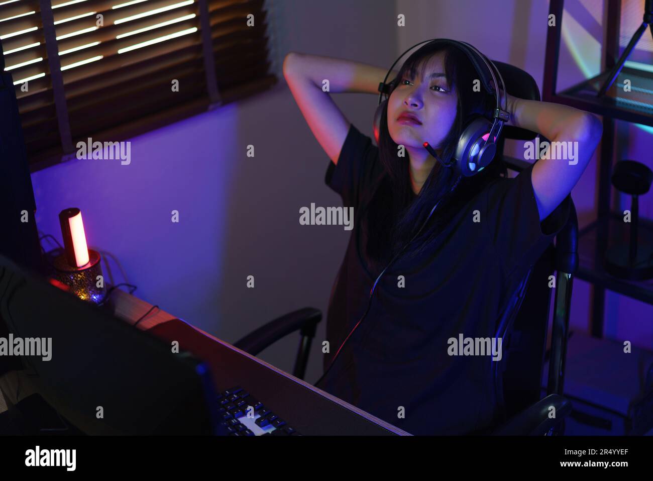 Female cyber hacker gamer holds hands behind head to resting after ...