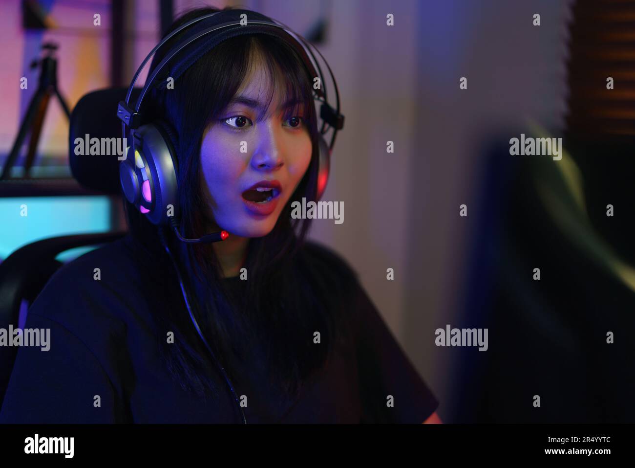 Female cyber hacker gamer in headphone excited while playing games or hacking programming system ...