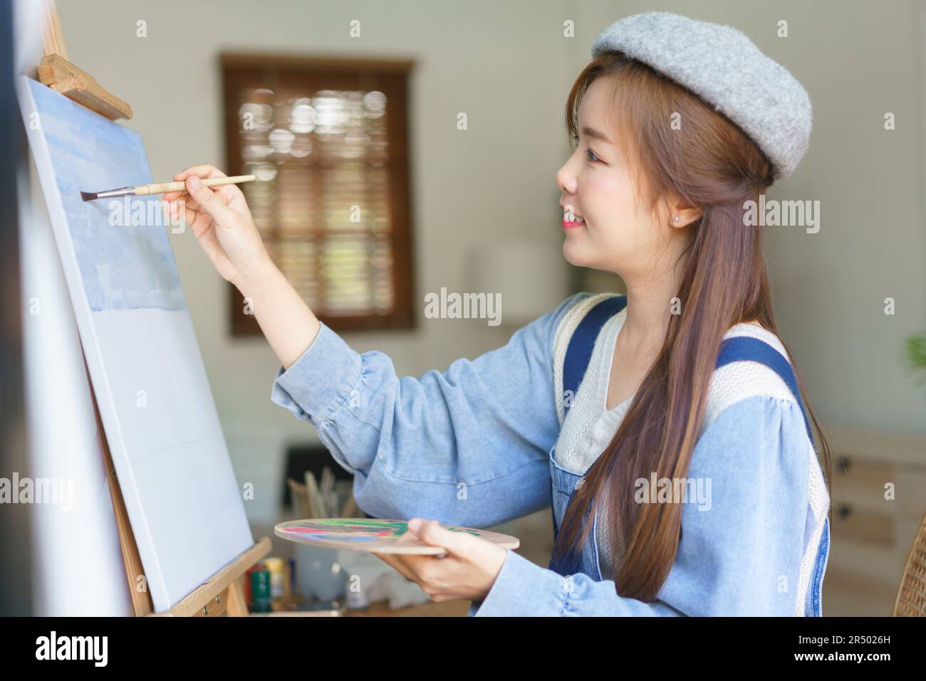 Young female artist creation to drawing and painting artwork on canvas ...