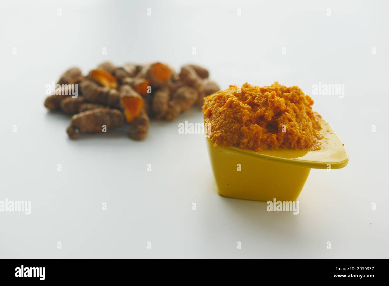 turmeric root and paste in a bowl on white background Stock Photo - Alamy