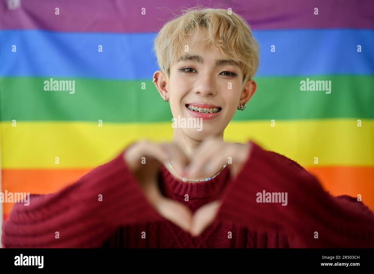 An attractive and smiling young Asian queer or gay man showed the heart ...