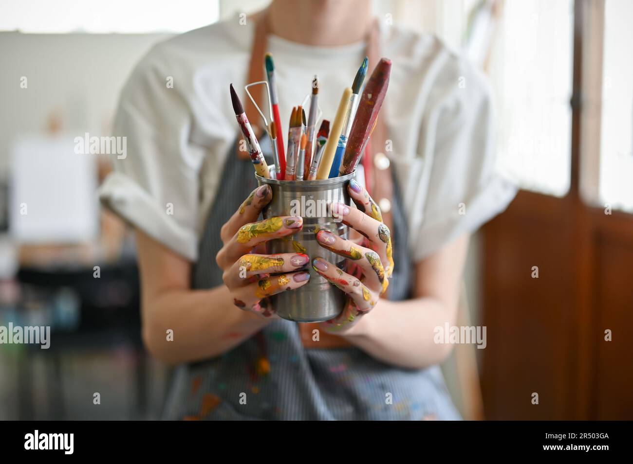 Close-up image of a young male artist in an apron holding a pencil ...