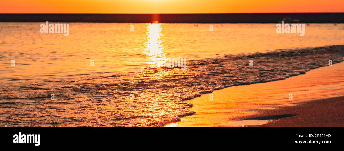 Reflection of sunlight over sea surface at sunset. Orange and gold blue ...