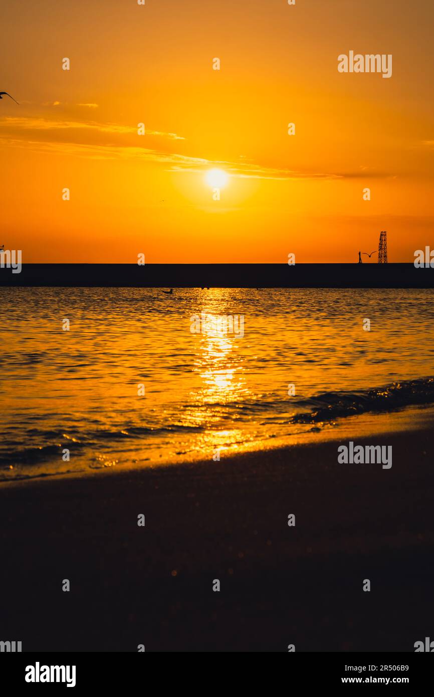 Reflection of sunlight over sea surface at sunset. Orange and gold blue ...