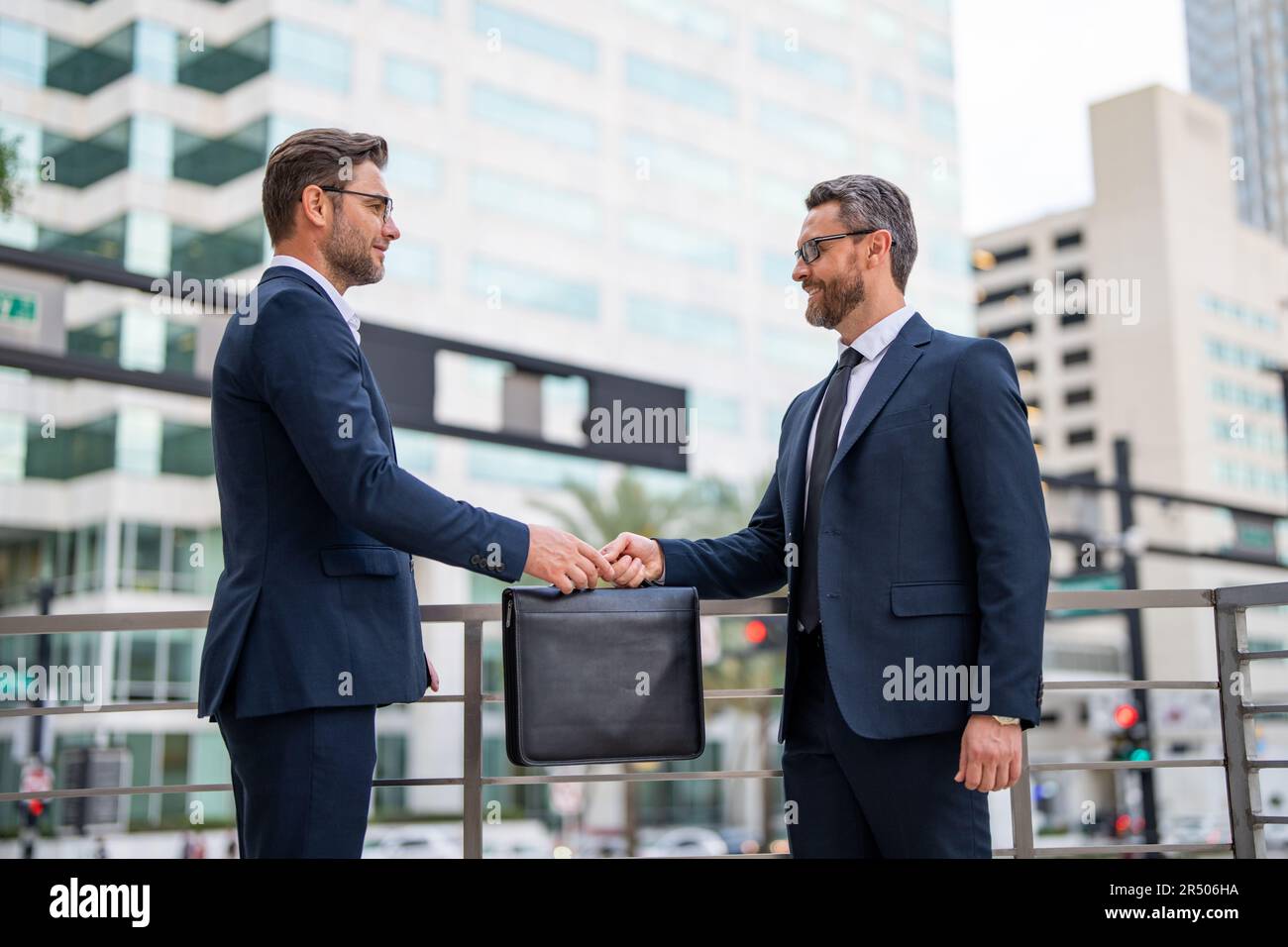 Business deal. Two business man hold business briefcase outdoor ...