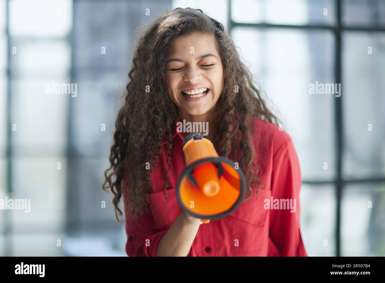 Beautiful girl shouting into a megaphone in a modern office Stock Photo ...