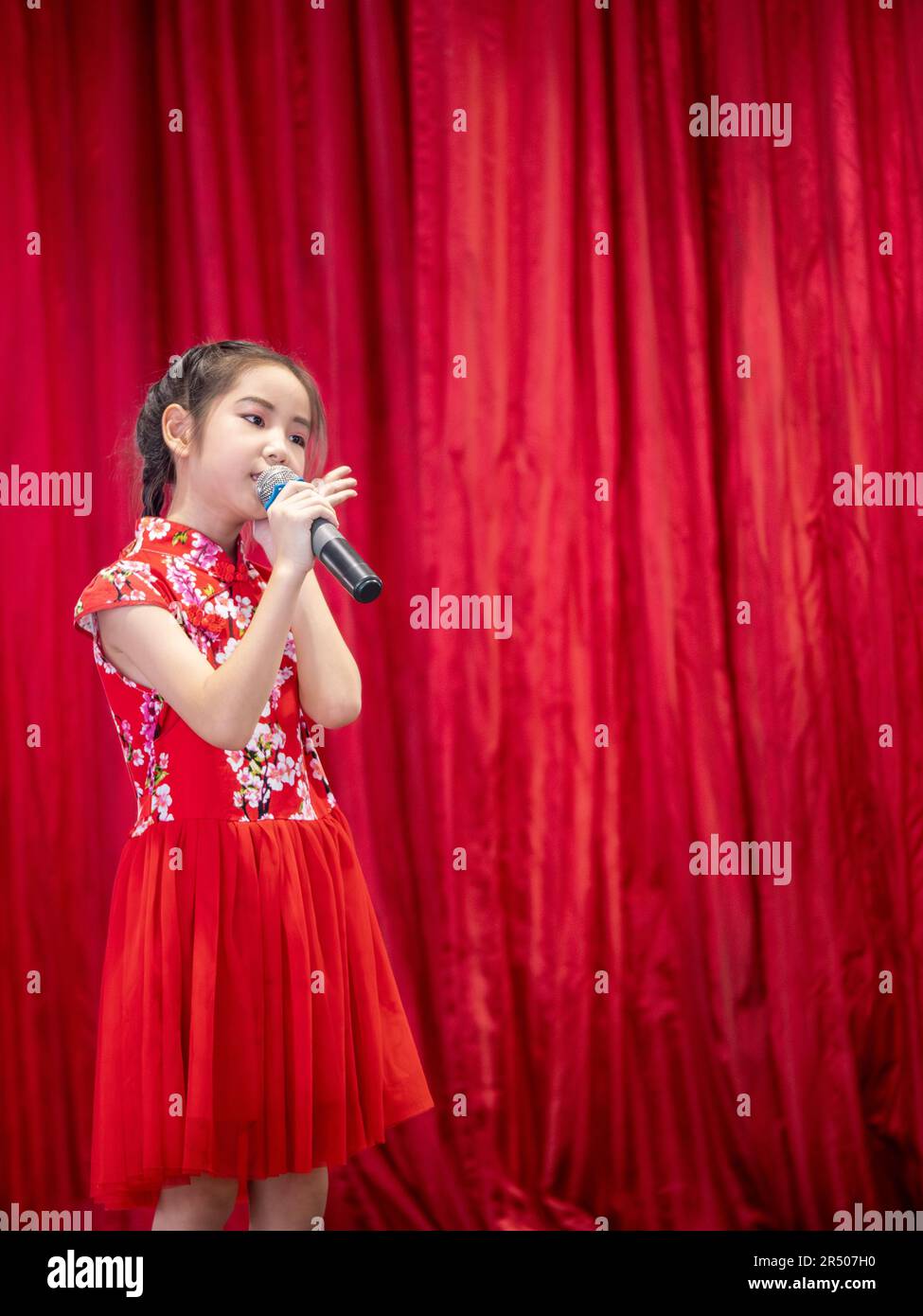 The Asian kid girl sing a song on stage at her school activity day ...