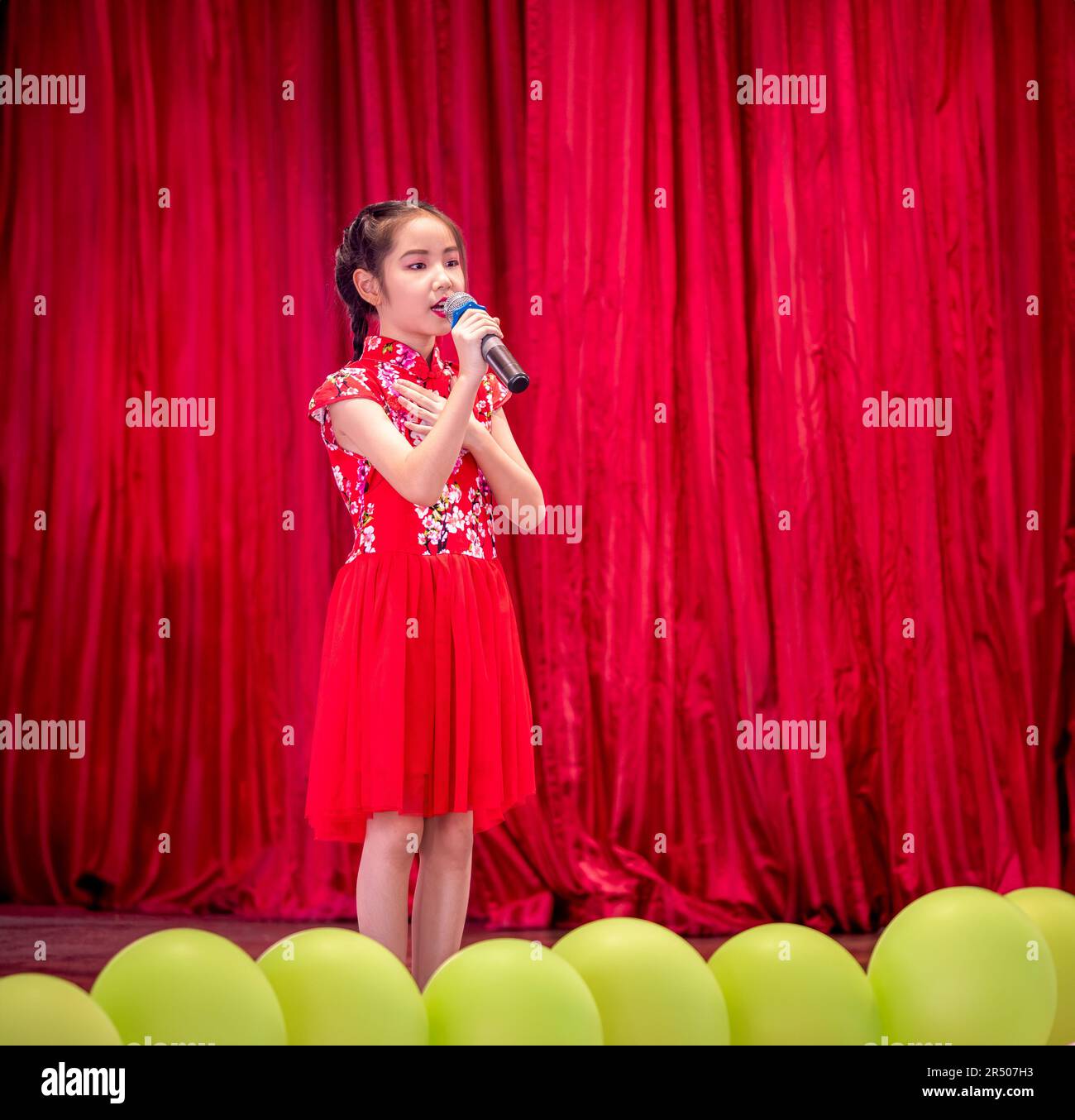 The Asian kid girl sing a song on stage at her school activity day ...