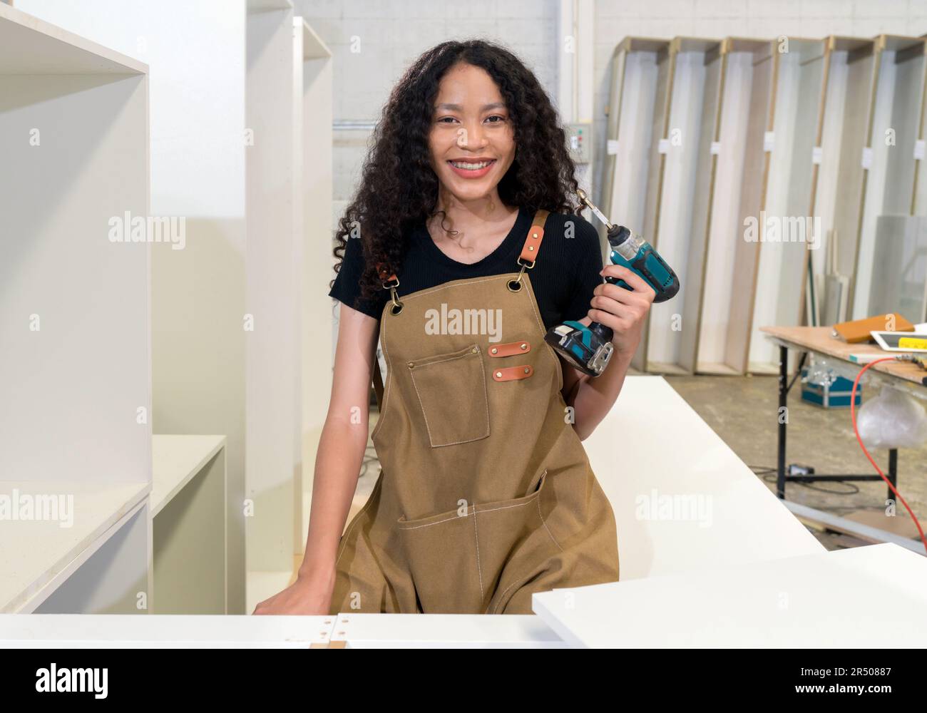 Teenager in brown apron holding cordless electric drill with battery ...