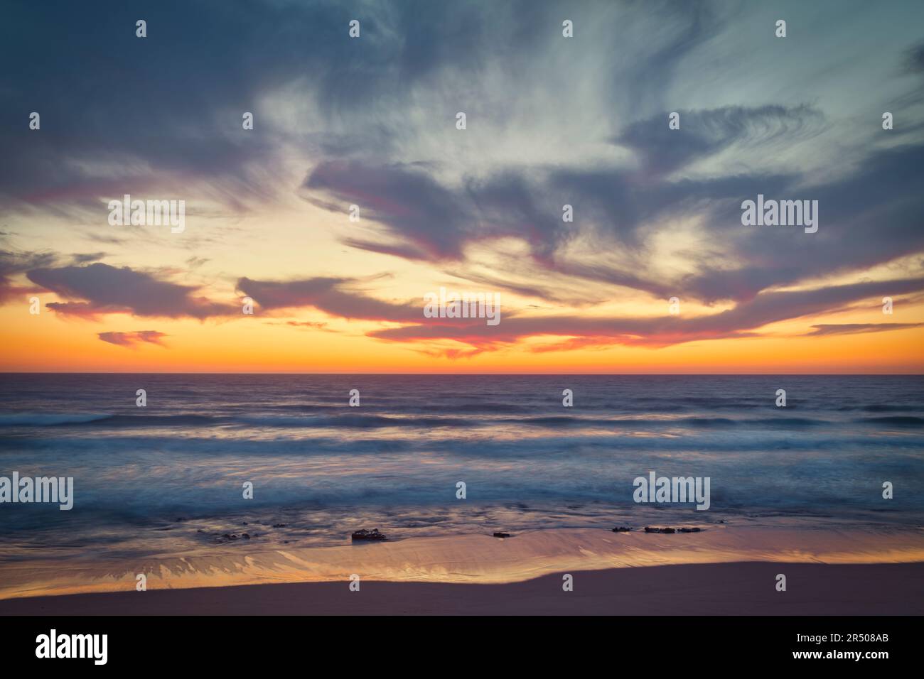 the moment after a beautiful sunset over a beach with pink clouds ...