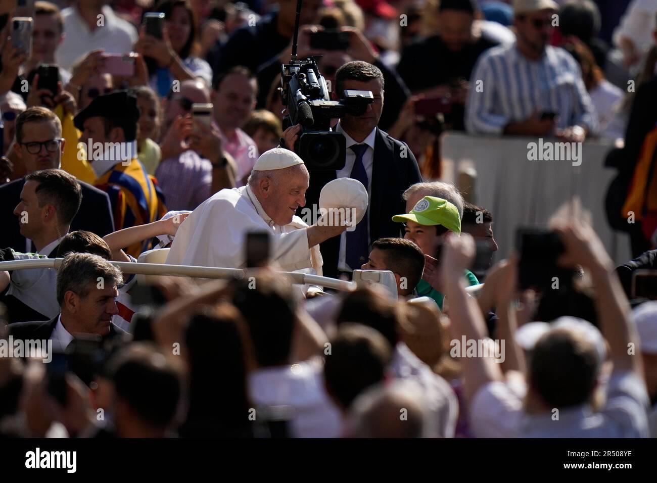 Pope Francis holds a skull-cap donated by faithful as he arrives for ...