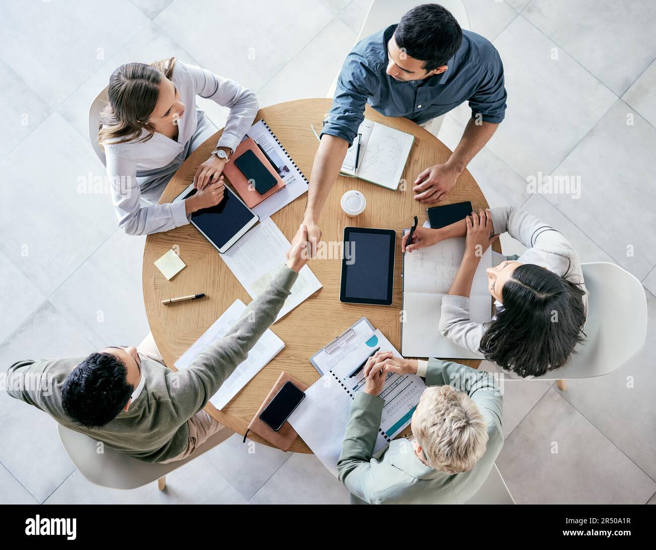 Meeting, handshake and overhead with a business team sitting around a ...